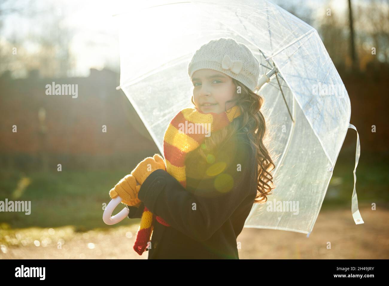 little girl in a blue coat with a white umbrella in the park in autumn ...