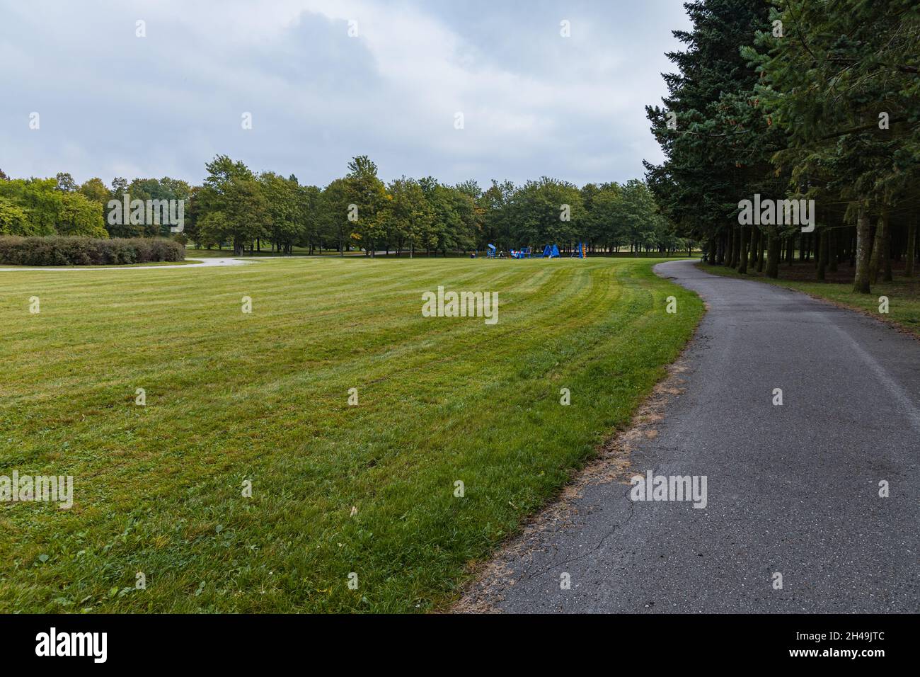 Long asphalt path in Citadel park with trees and lamps around next to ...