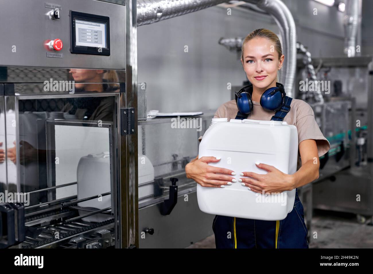 woman worker in factory next to robotic equipment holding canister ...
