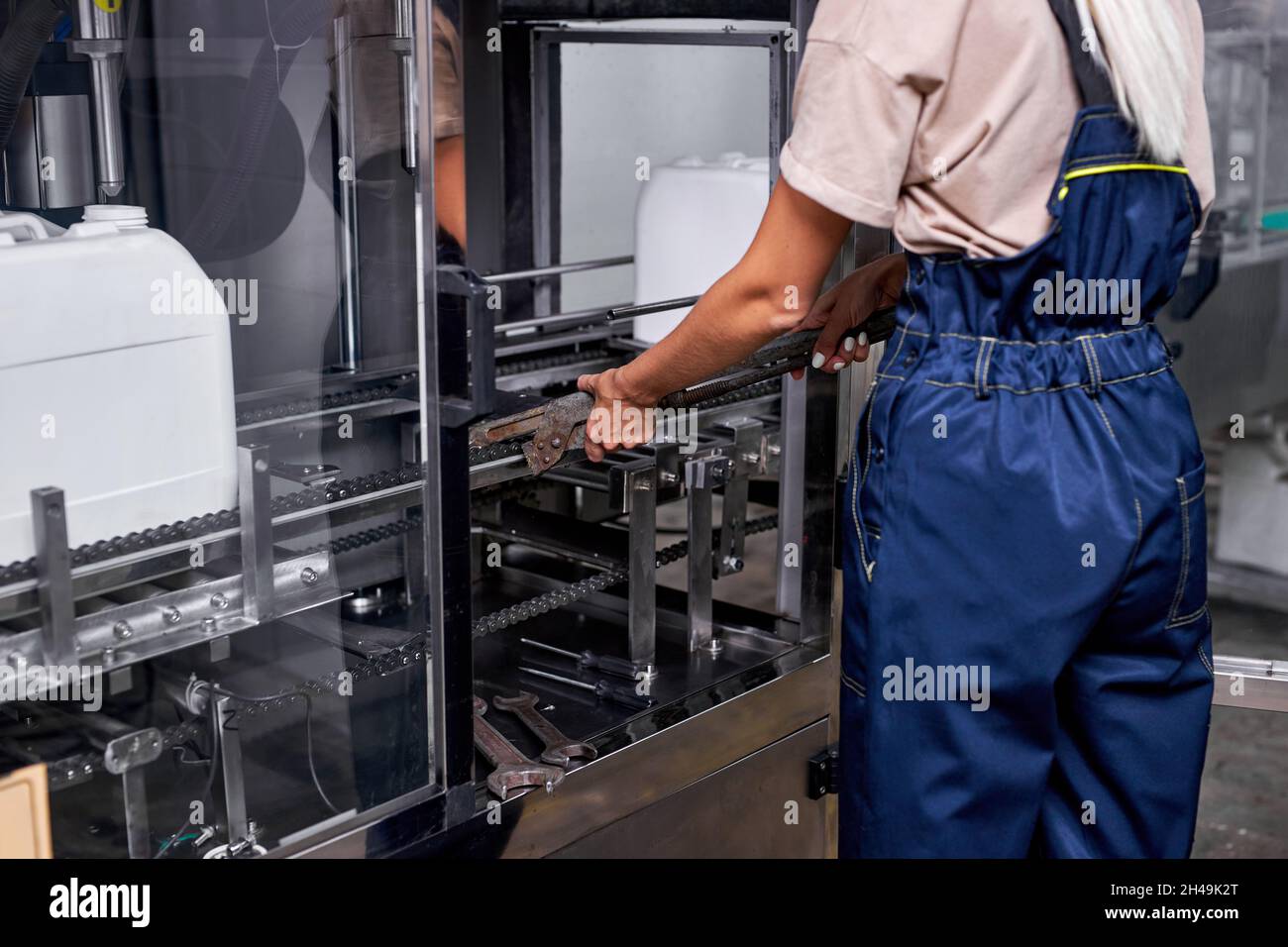 worker in factory preparing robotic line for bottling and packing ...