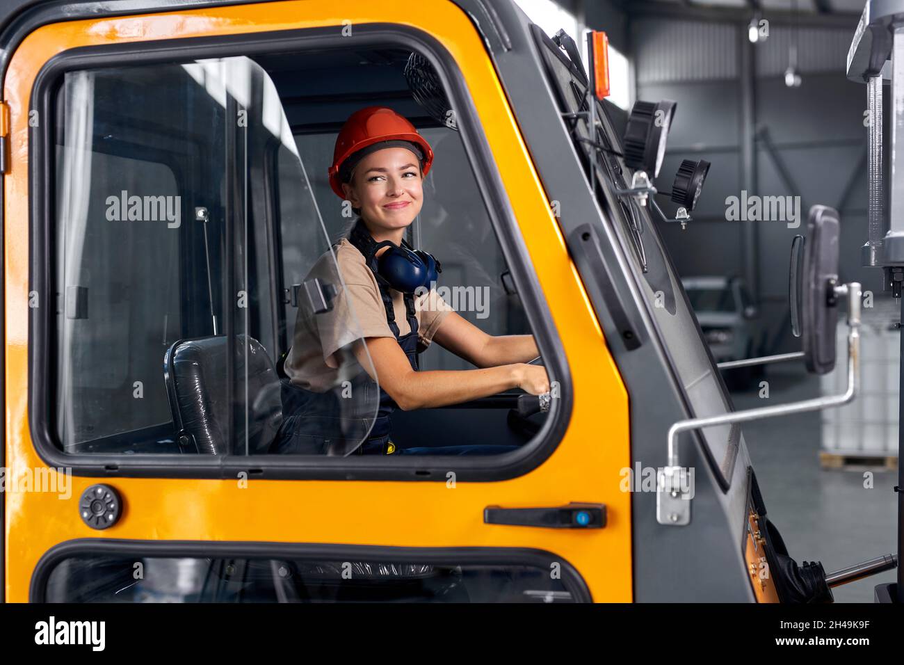 Beautiful woman forklift worker operator driving vehicle at warehouse ...