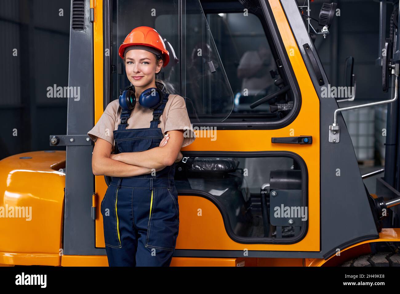 smiling female labor worker near forklift driver in industry factory ...