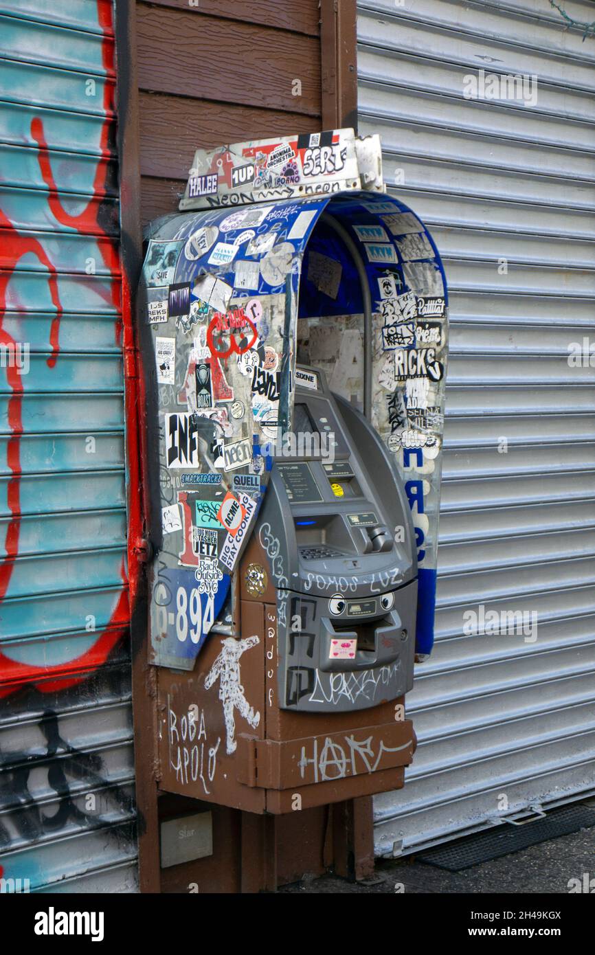 An ATM cash machine covered in graffiti, tags and stickers. On Grand ...