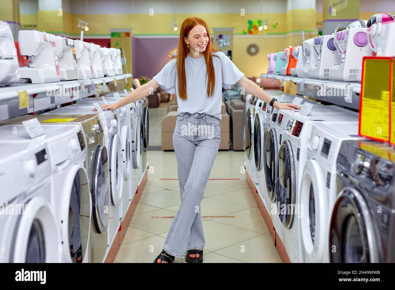 Adorable lady in casual outfit stand by new washing machines, make ...