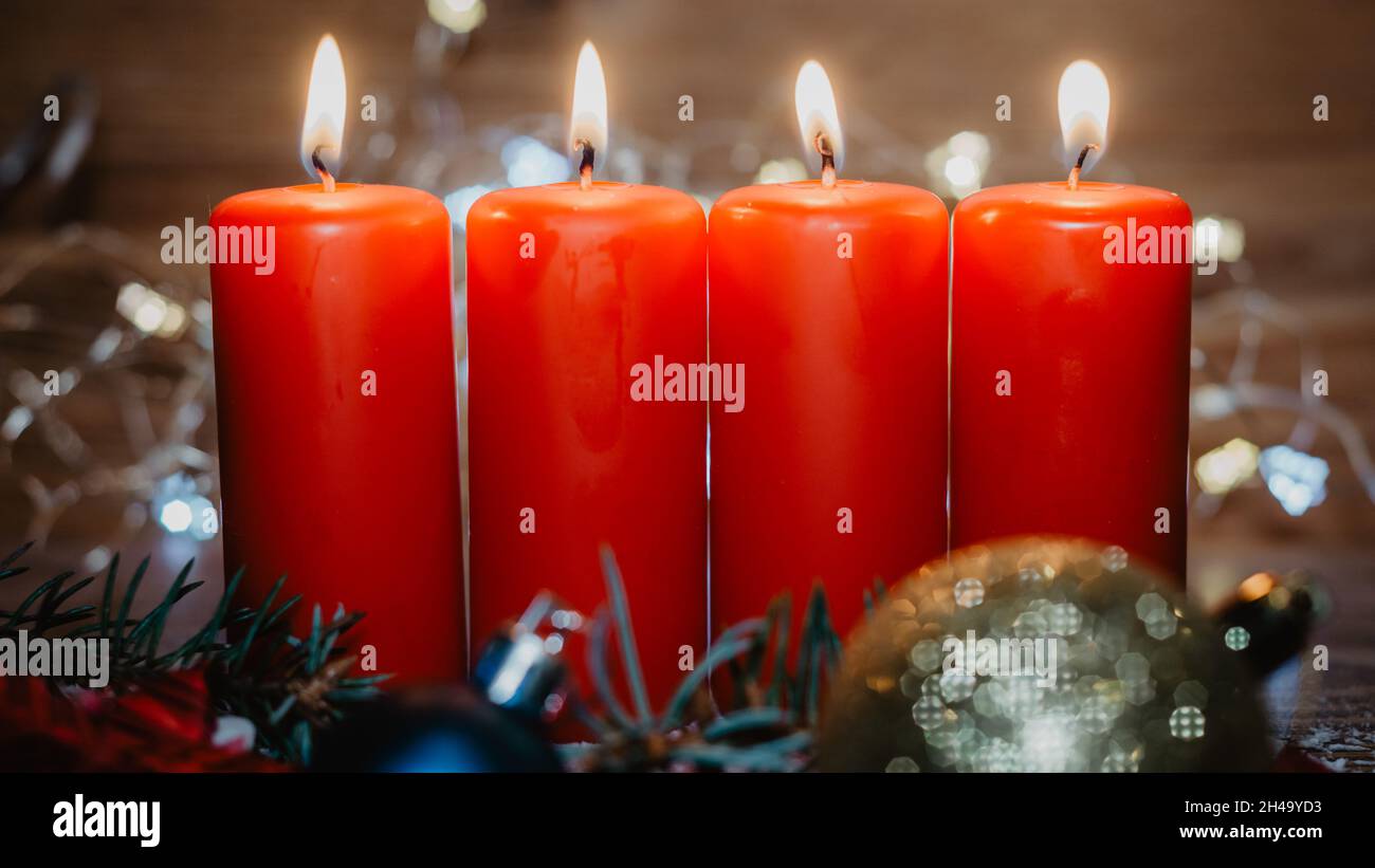 Four red advent candles with four candles lit and christmas decoration ... Four red advent candles with four candles lit and christmas decoration ...