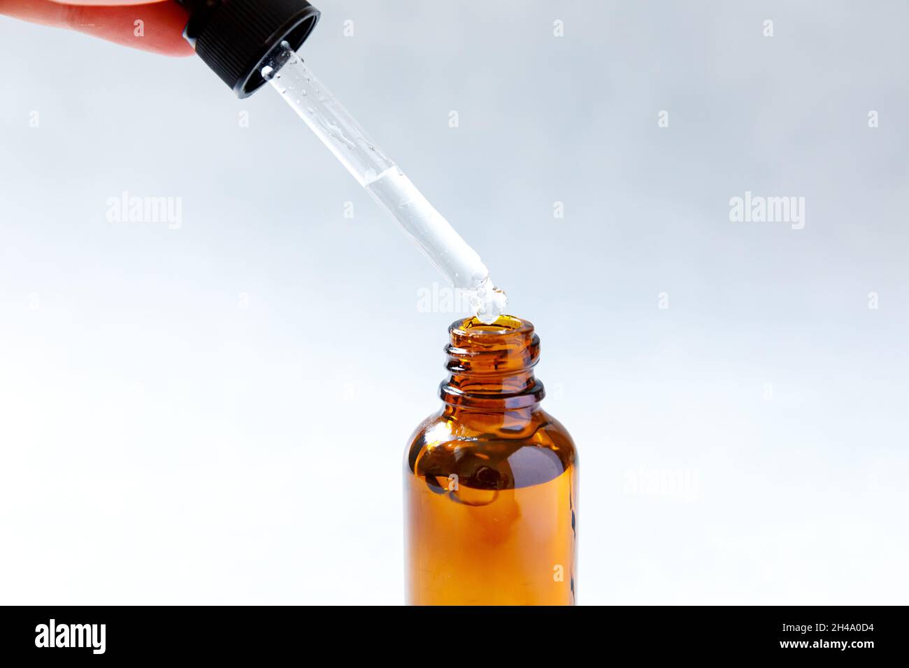 Essential oil dropping from pipette to bottle. Essence liquid cosmetic ...