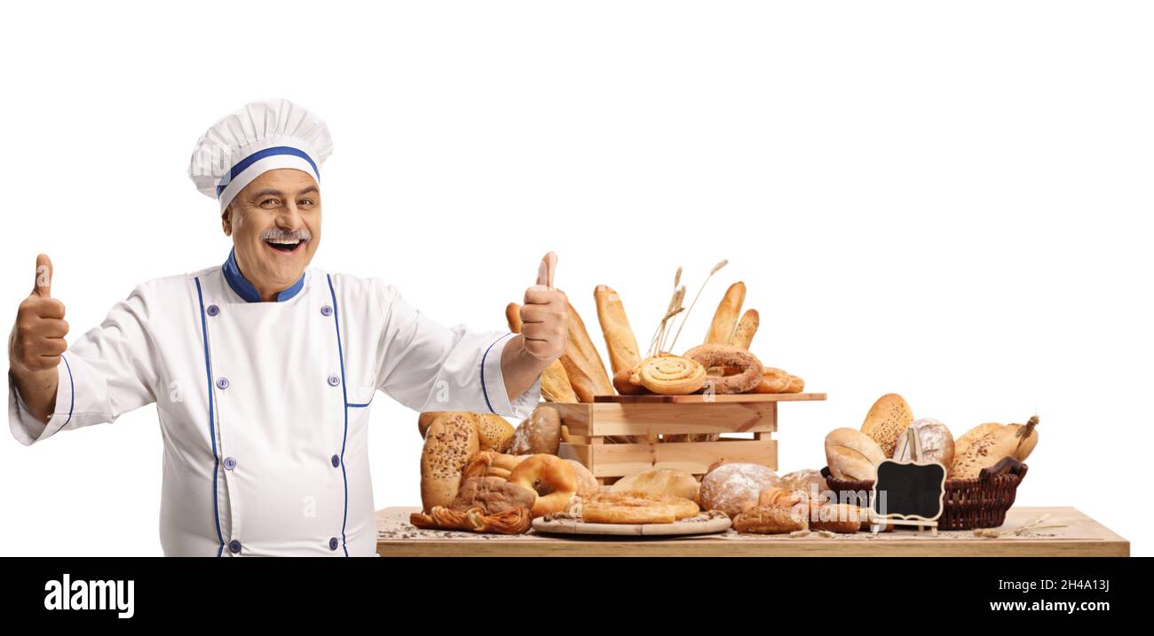 Cheerful male chef with a variety of bread loaves smiling and showing ...