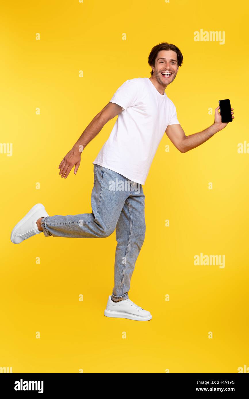 Cool Mobile Offer Ad. Joyful young casual guy showing empty cell phone ...