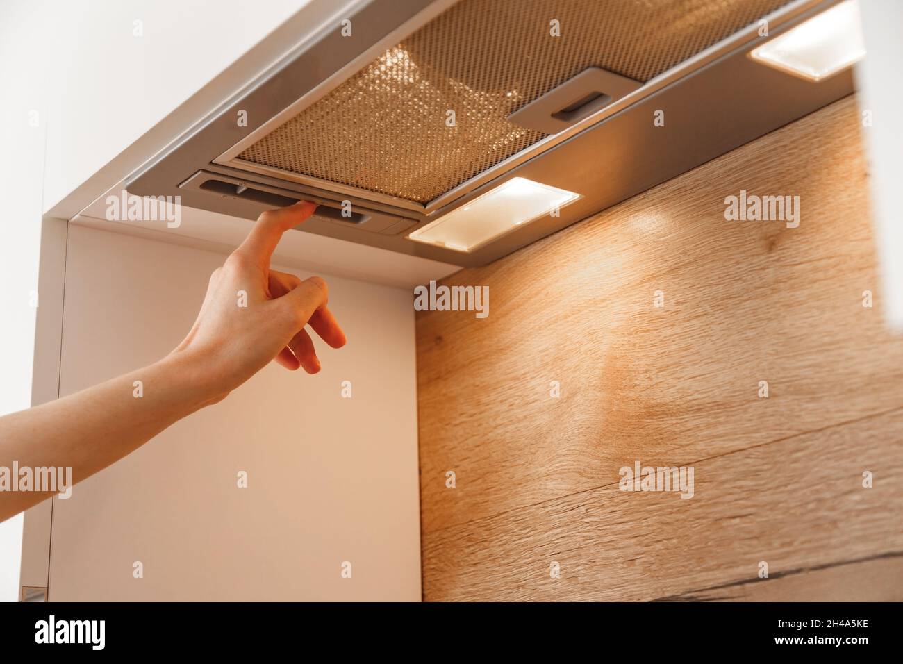 Woman hand turn on embedded cooker hood in white modern kitchen Stock ...