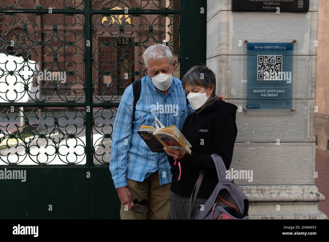 Foreign tourists wearing protective masks reading a guide book outside ...