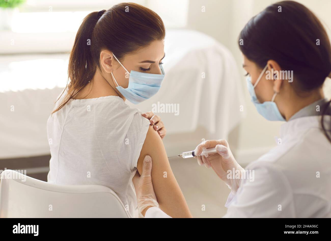 Young woman in medical face mask getting flu or Covid vaccine injection ...
