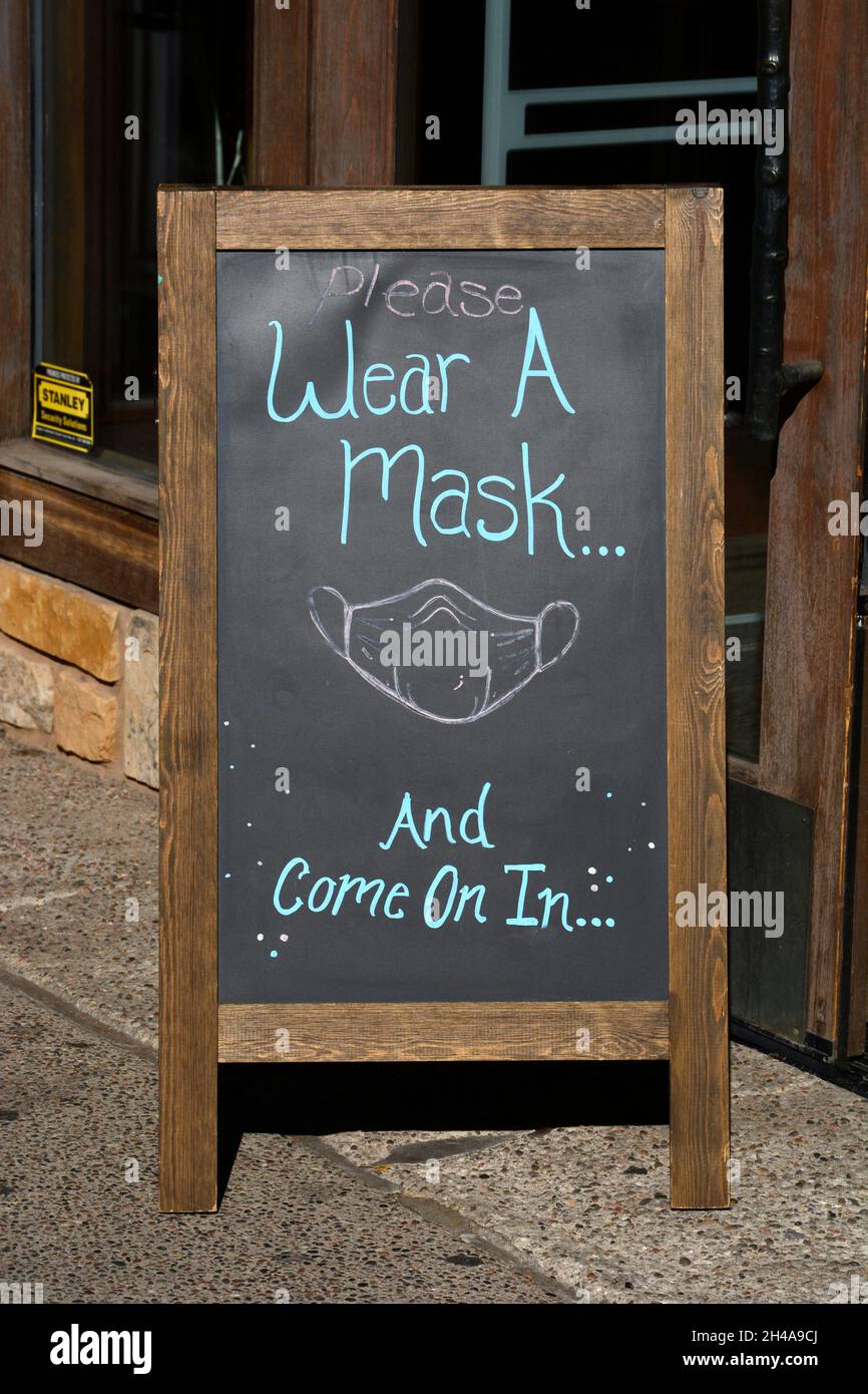 A sign outside a shop informs customers they must wear masks when ...