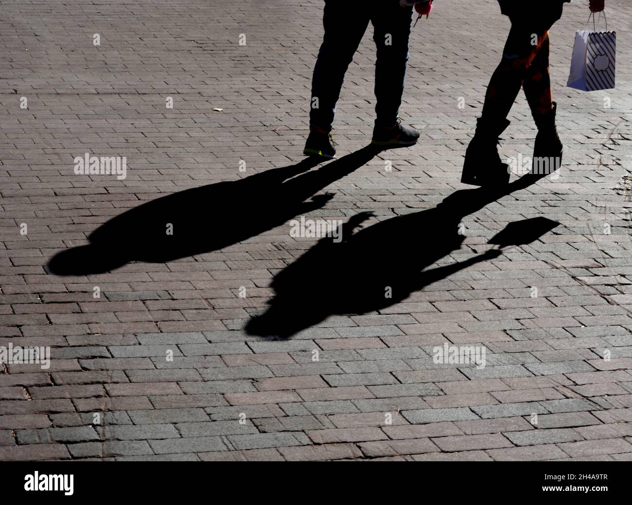 Two women shoppers cast long shadows as they visit shops in Santa Fe ...