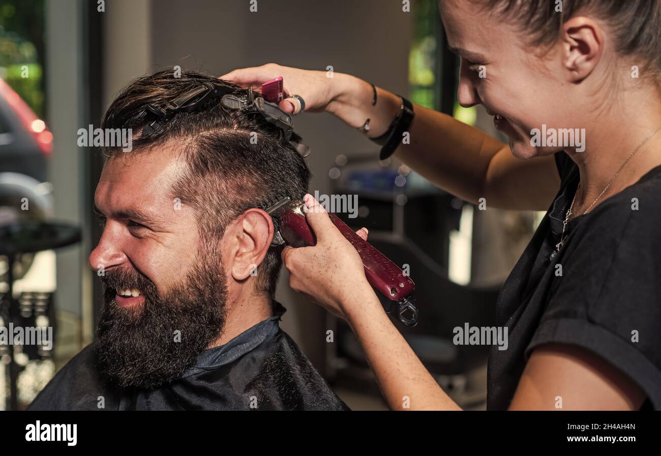 attractive barber making haircut of handsome guy in barbershop ...