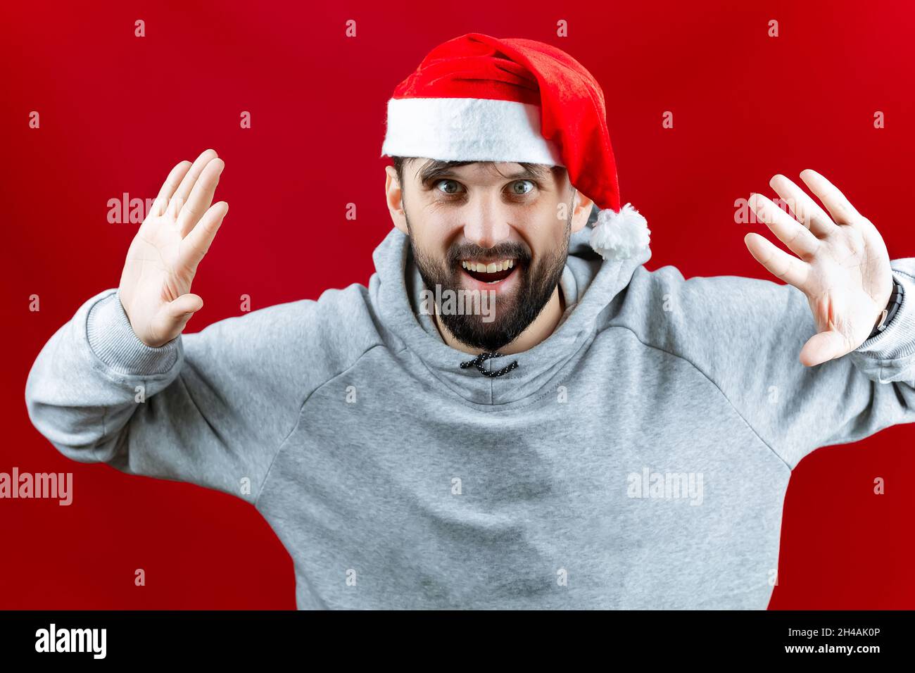 a cheerful man dressed in a Santa Claus hat smiles and shows his teeth ...