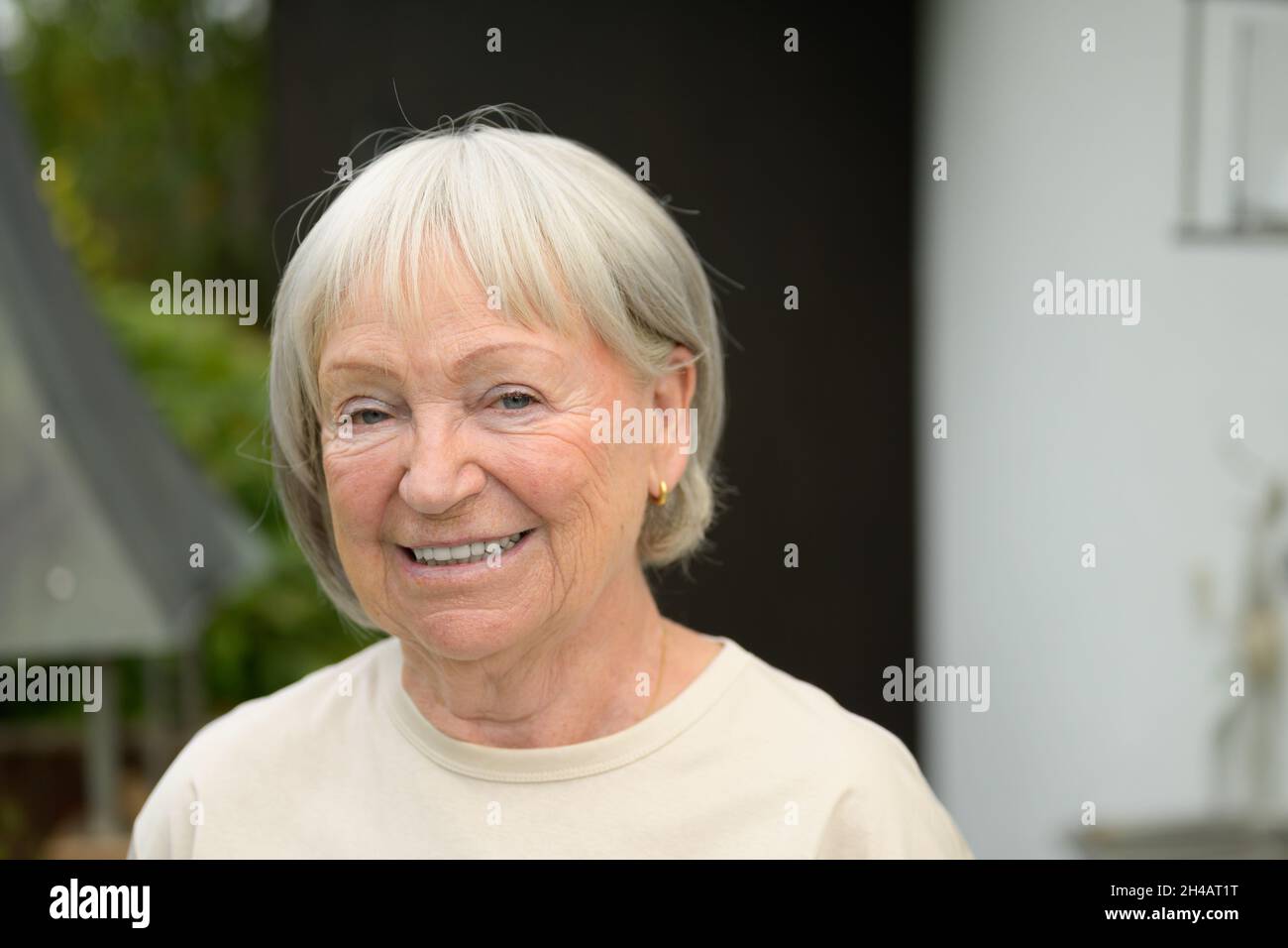 Headshot of a smiling friendly senior woman outdoors looking into the ...
