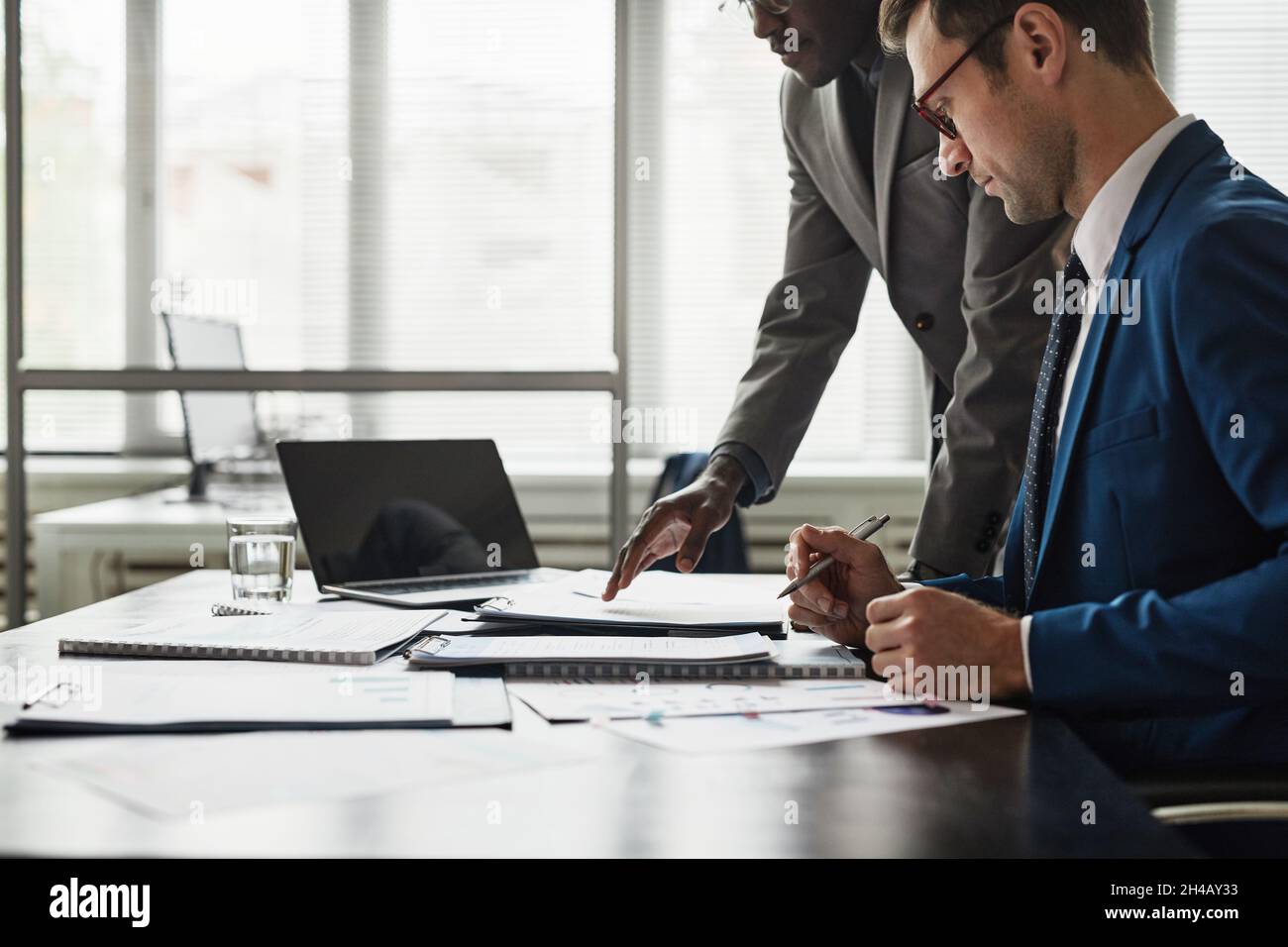 Side view of two businessmen discussing contract at table during ...