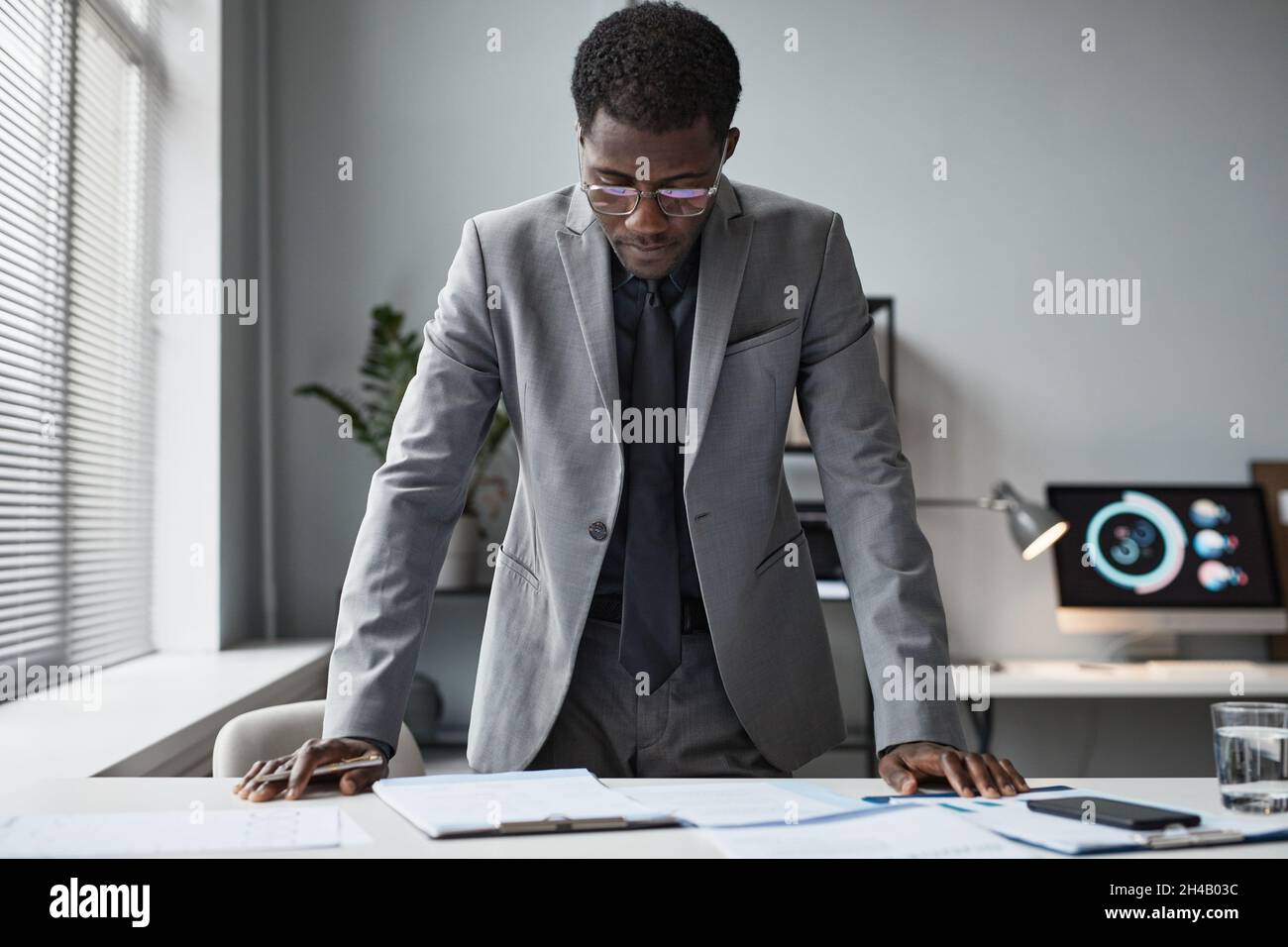 Portrait of successful black businessman leaning over desk in office ...