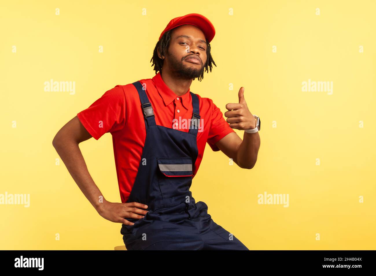 Portrait of handsome confident handyman wearing blue uniform, red visor ...