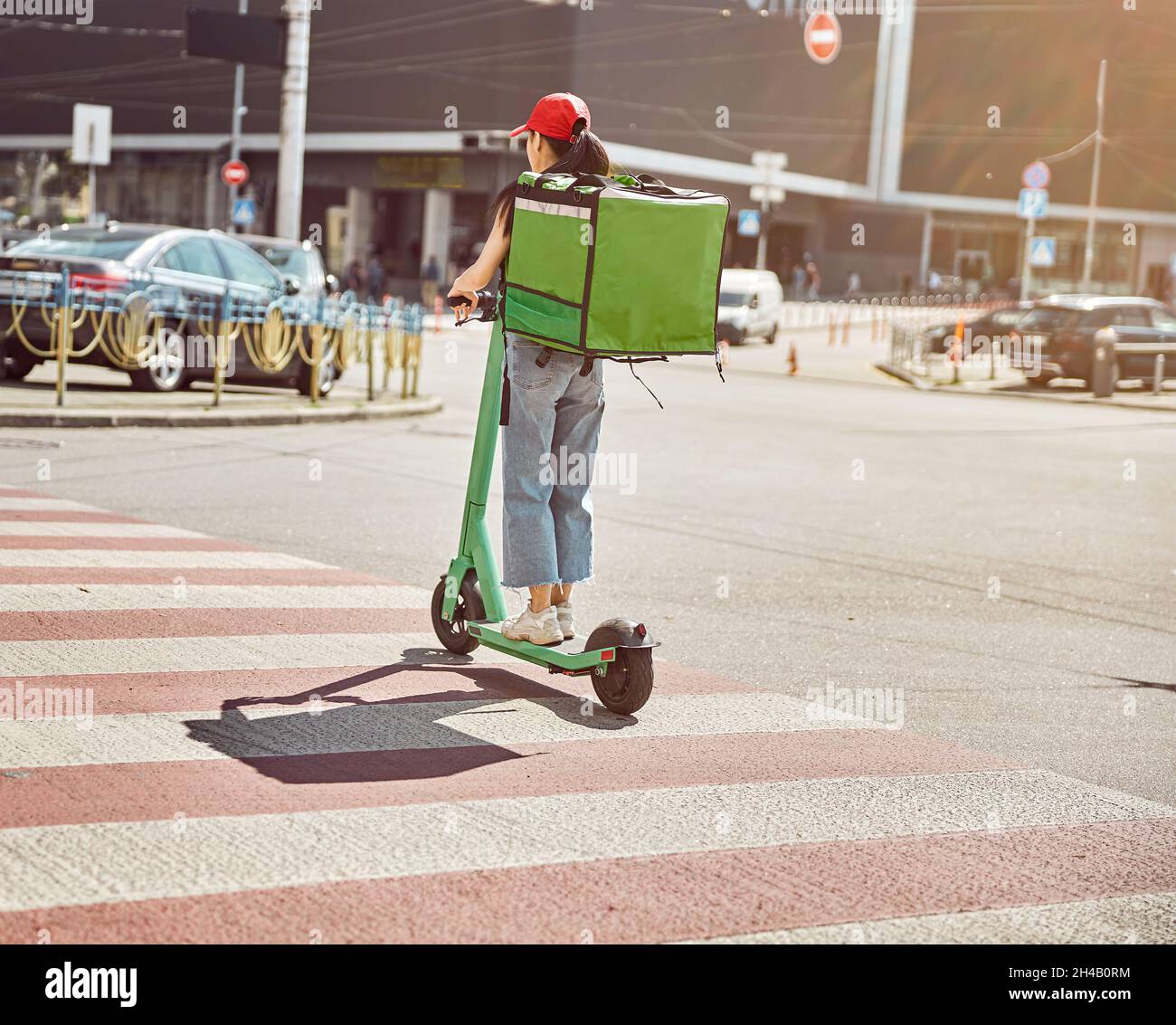Food delivery lady riding scooter in modern city Stock Photo - Alamy