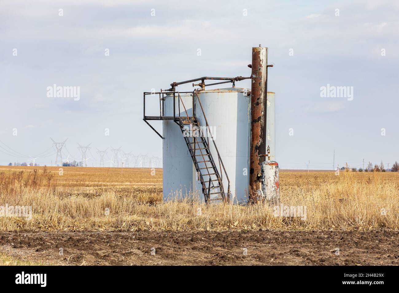 Old oil well storage tanks in farm field. Oil well abandonment ...