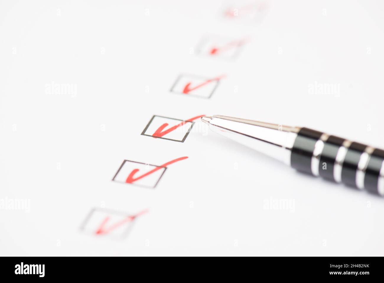 Red colored checkmarks in little black boxes, white paper, education ...