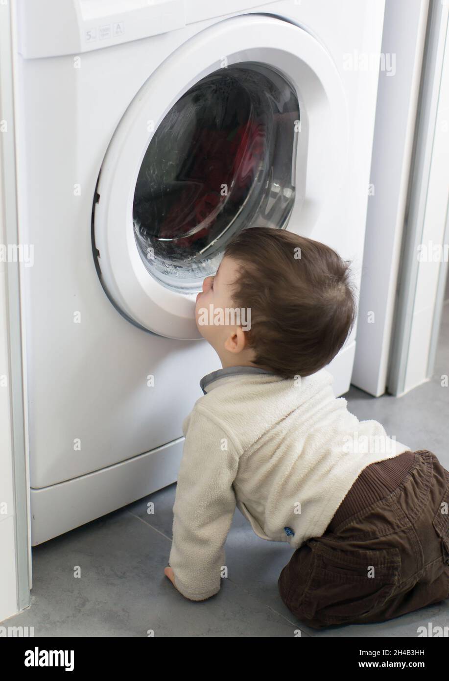 Little toddler looking into a washing machine Stock Photo - Alamy