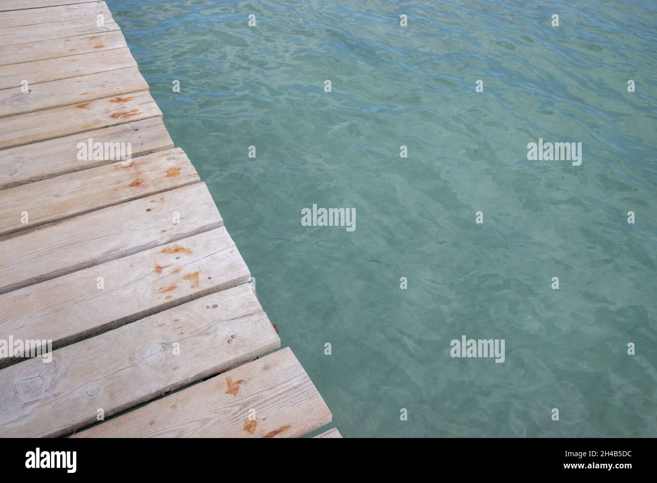 A wooden boardwalk planks of wood from a pier going over the ocean or ...