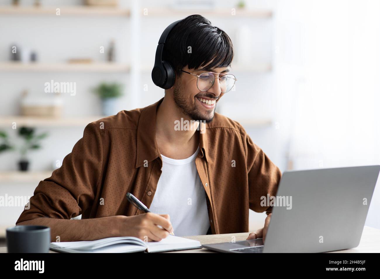 Young arabic man having online class from home, sitting in front of ...