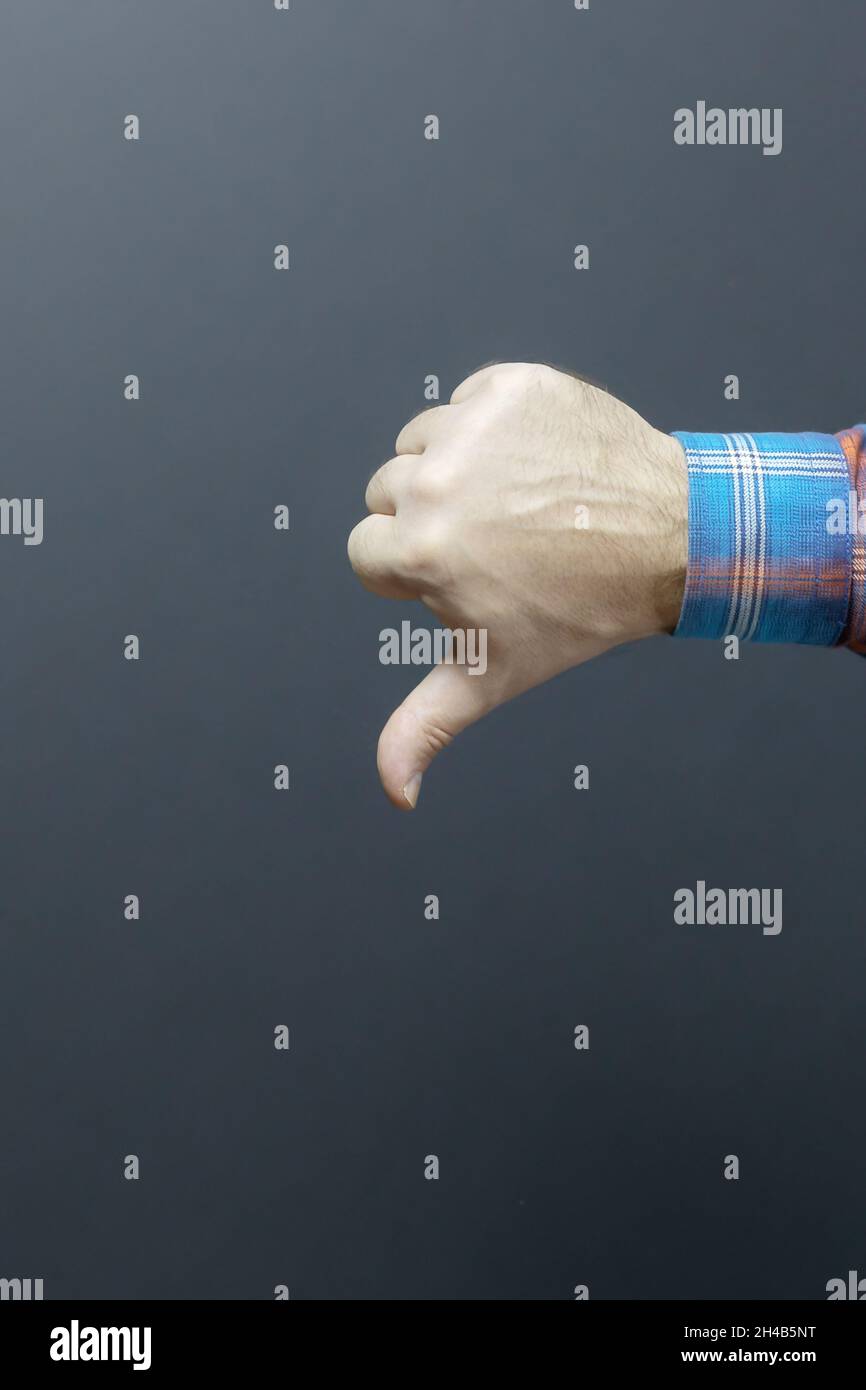 Male hand shows thumb down on gray background. Bad gesture Stock Photo ...