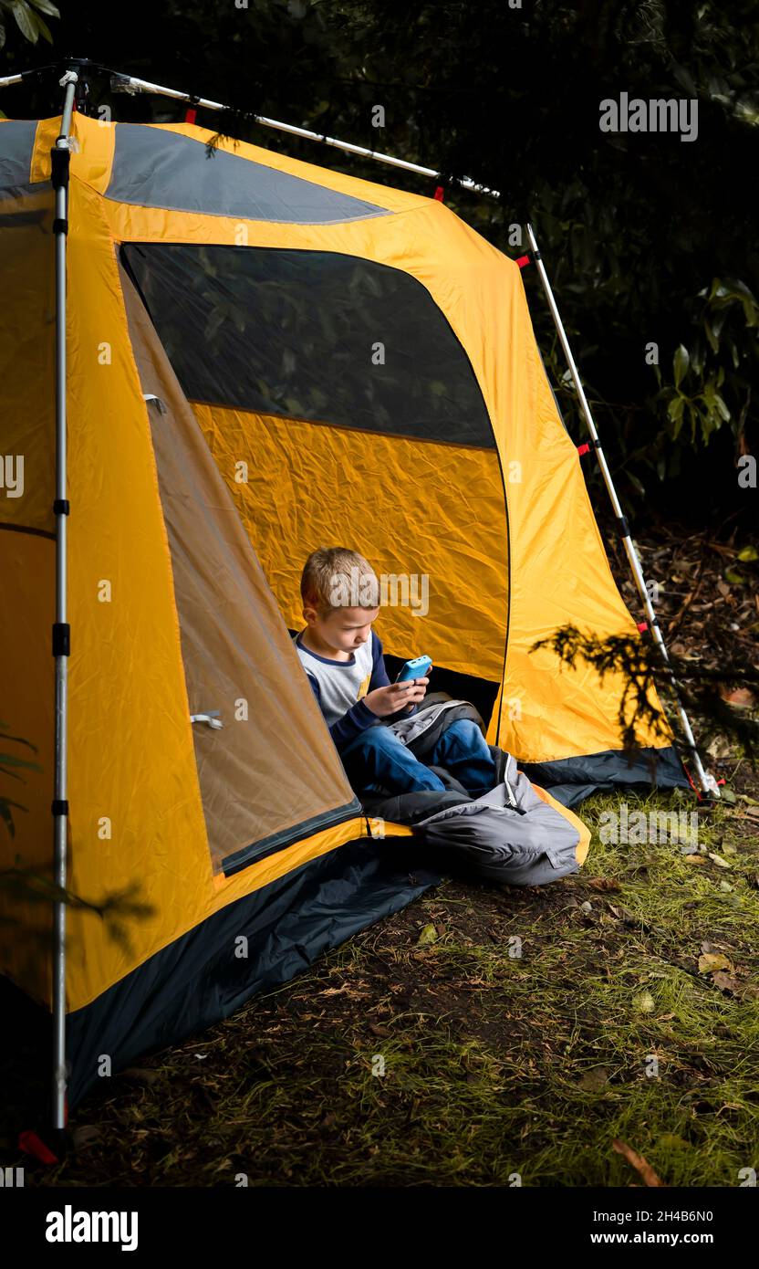 Boy playing on retro game console in tent at campsite Stock Photo - Alamy