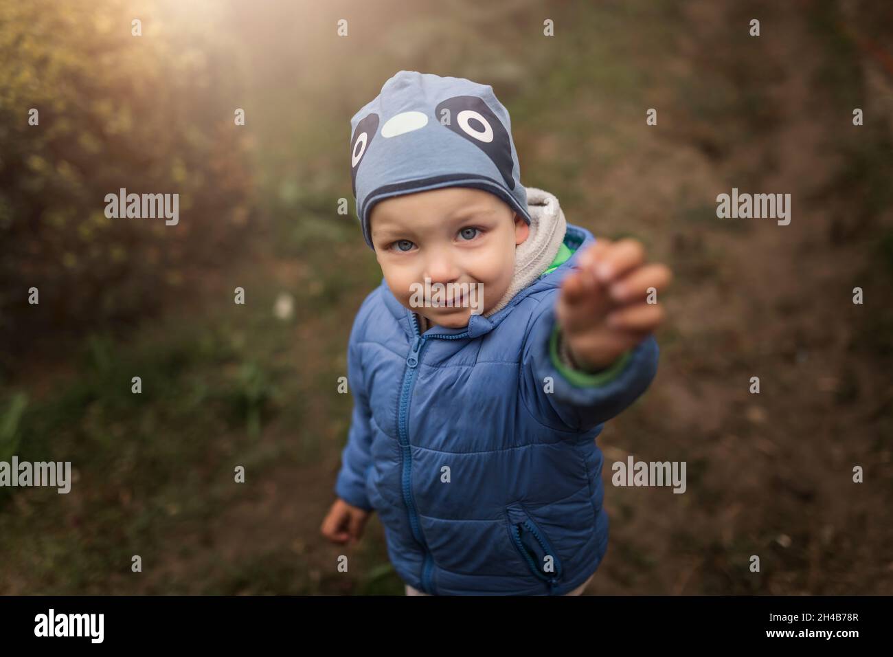 Small child in garden trying to reach something with his hand Stock ...