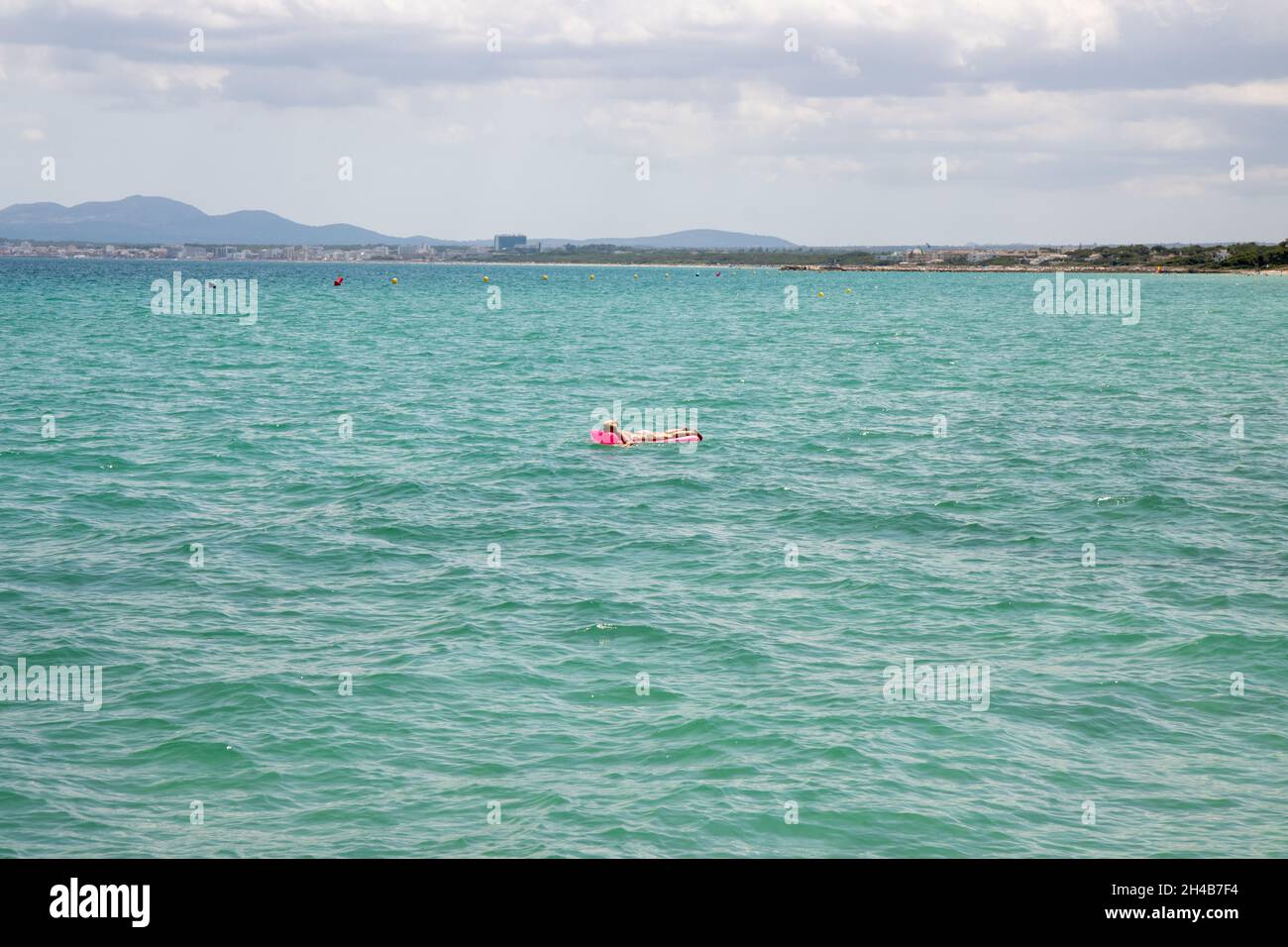 A middle aged man swimming and laying down on a pool inflatable lilo in ...