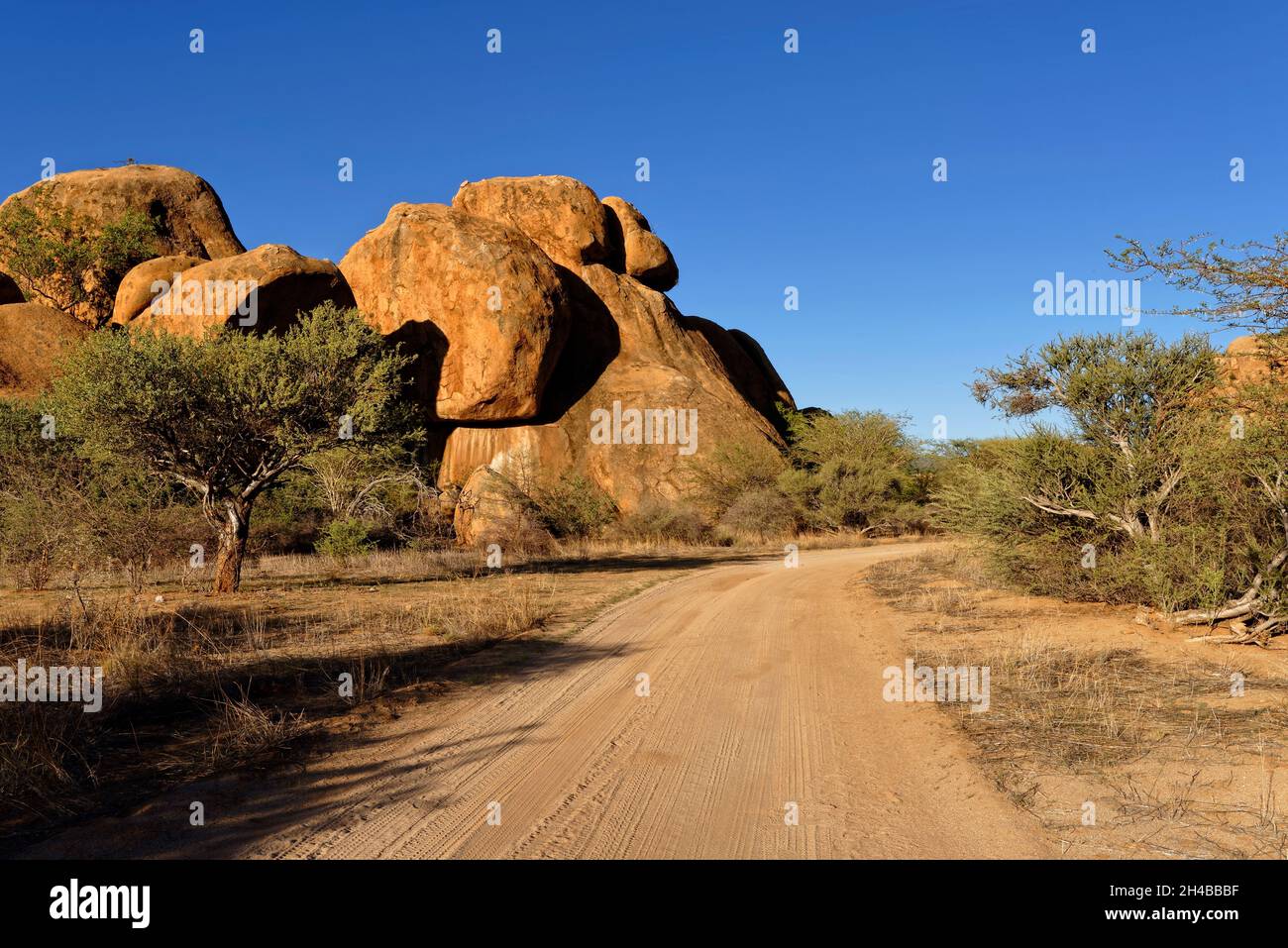 Farm Omandumba (guest farm): Farm road between granite rocks in the ...