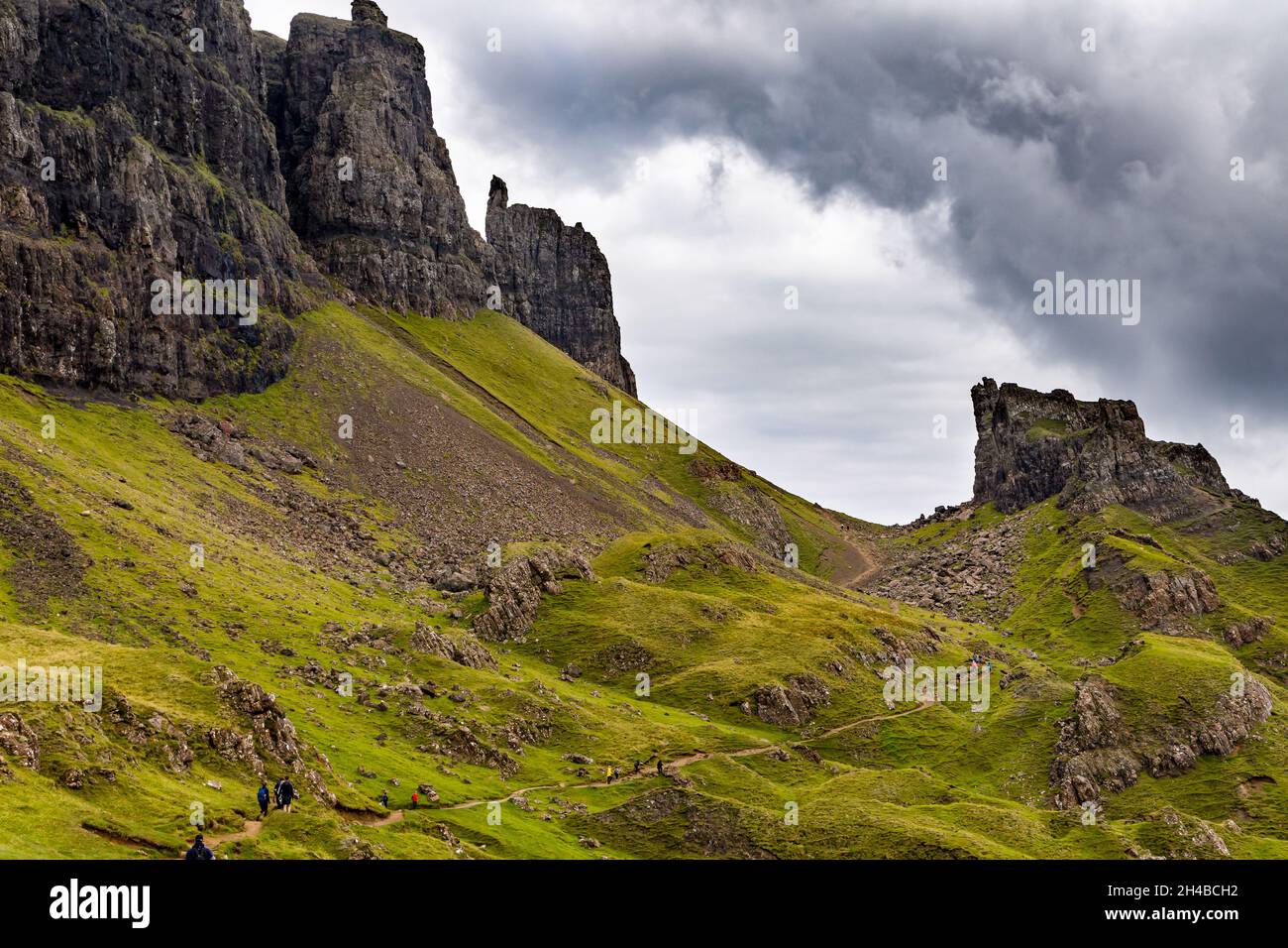 Hikers on a spectacular remote, rocky landscape with a low, moody sky ...