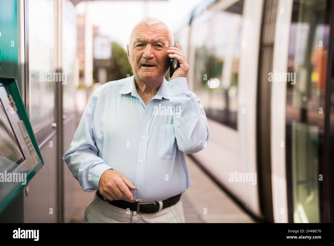 Old man talking on phone in tram station Stock Photo - Alamy