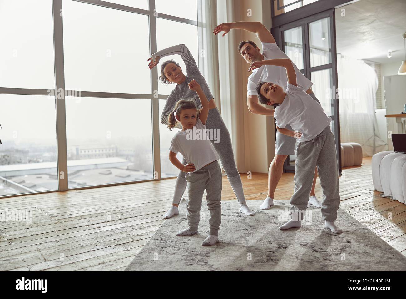 Joyful family doing morning gymnastics together at home Stock Photo - Alamy