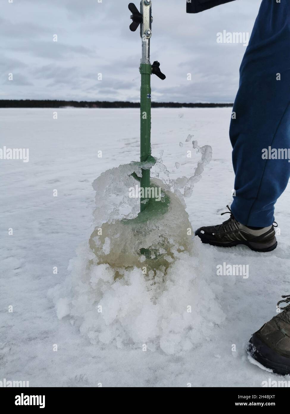 Drilling a hole into the thick ice for fishing in Finland Stock Photo ...