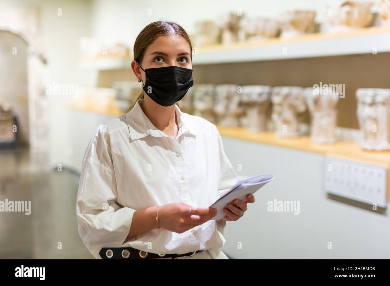 Woman in mask visiting exhibit at sculpture hall in museum Stock Photo ...