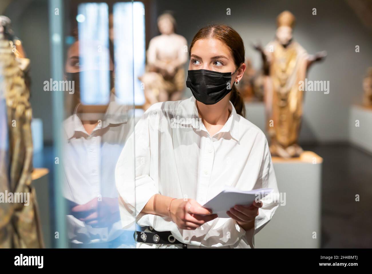 Woman in mask visiting exhibit at sculpture hall in museum Stock Photo ...