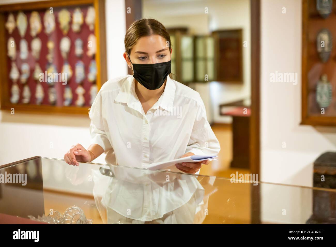 Woman exploring artworks in glass case in museum Stock Photo - Alamy