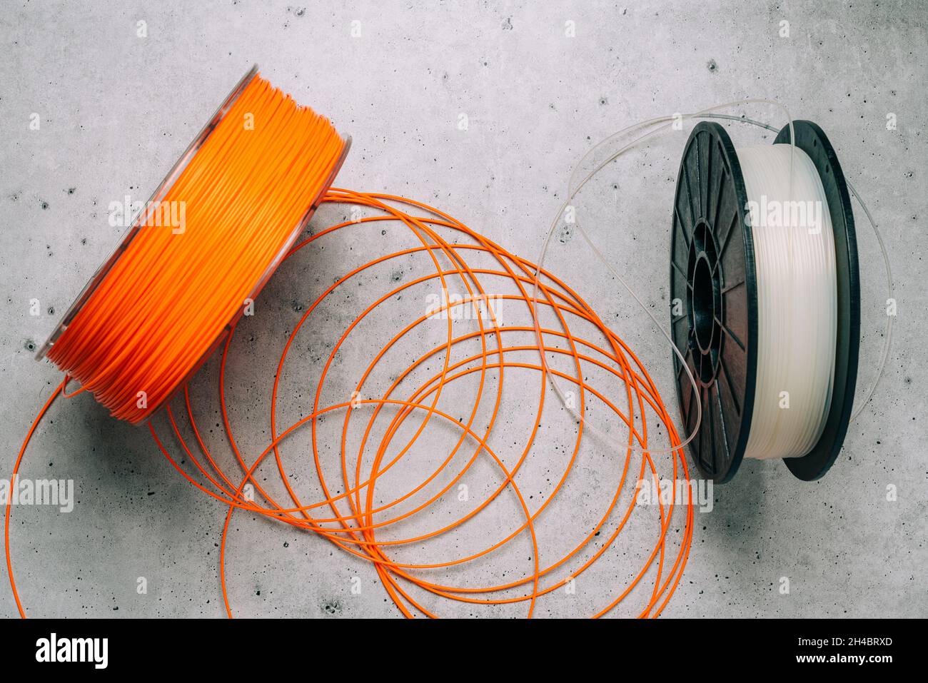 3D Printer Plastic Filaments. Spools of orange and white thermoplastic ...