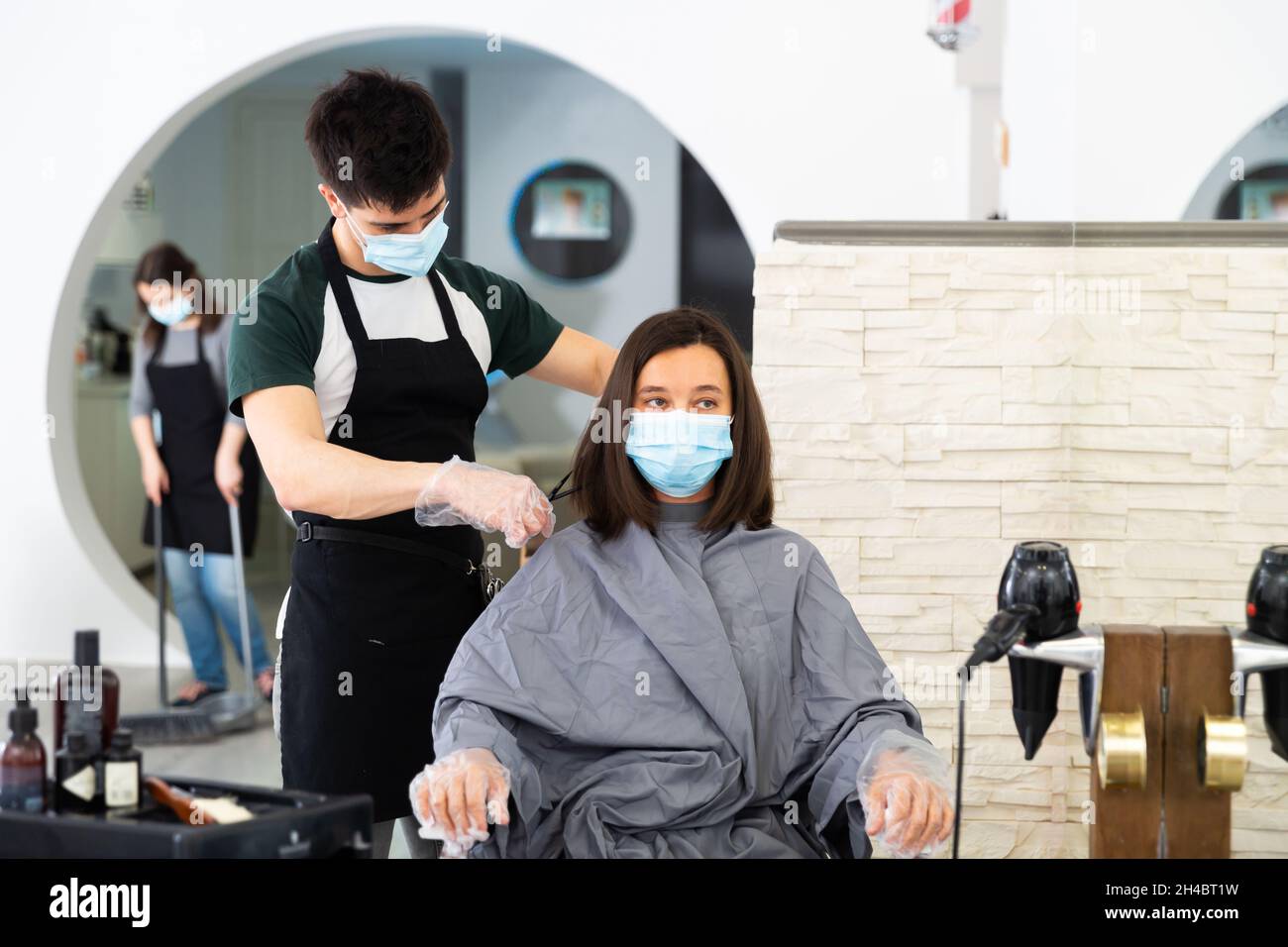 Man doing haircut for woman in salon using face masks Stock Photo - Alamy
