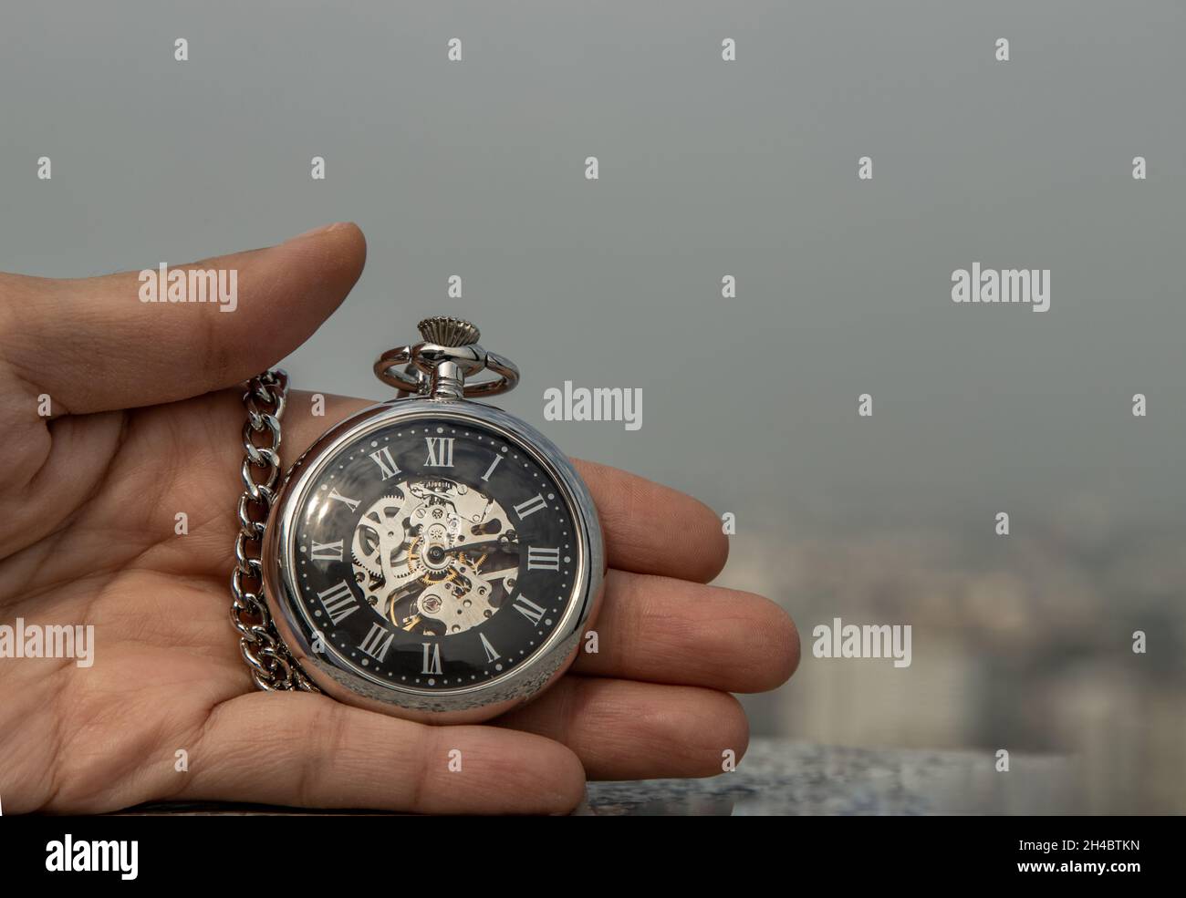 A retro pocket watch with chain in the palm of the girl's hand. Sky ...