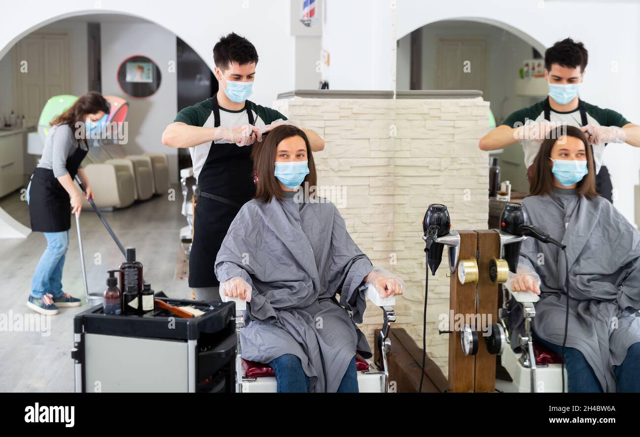 Man doing haircut for woman in salon using face masks Stock Photo - Alamy