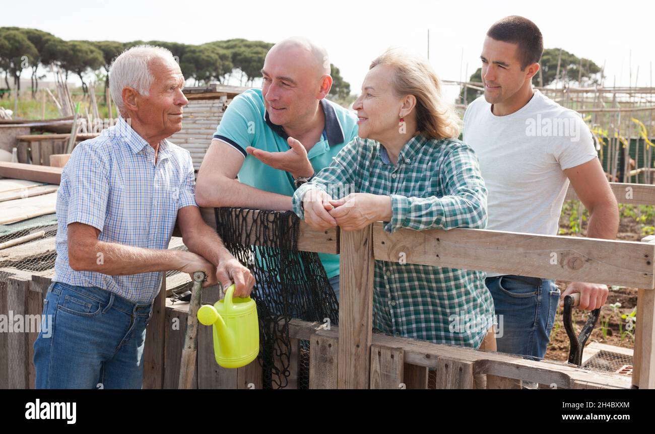 Farm neighbors talk at the border of the garden plot Stock Photo - Alamy