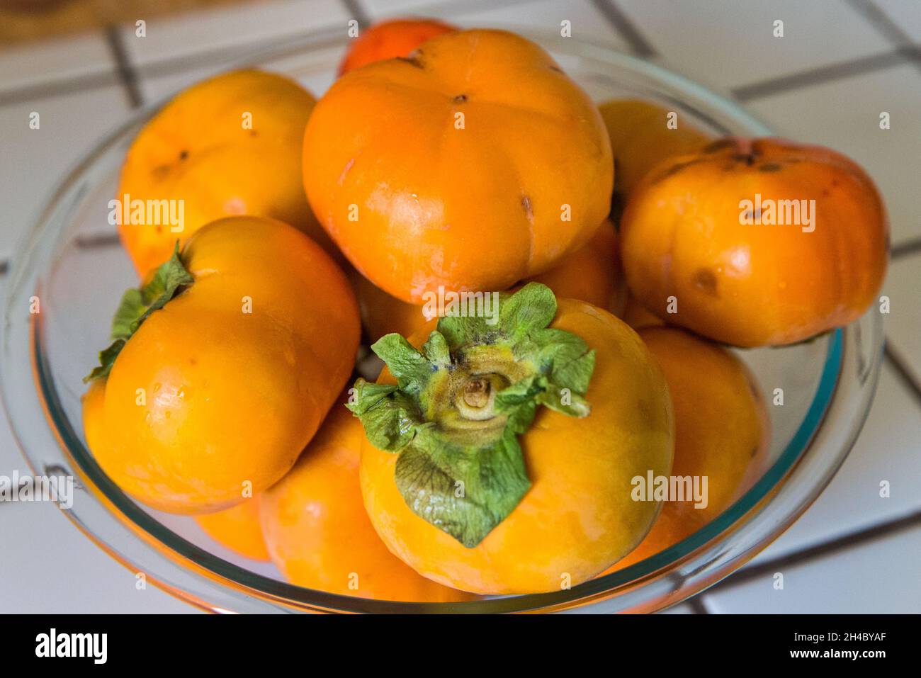 A bowl full of persimmons sits on a kitchen counter Stock Photo - Alamy
