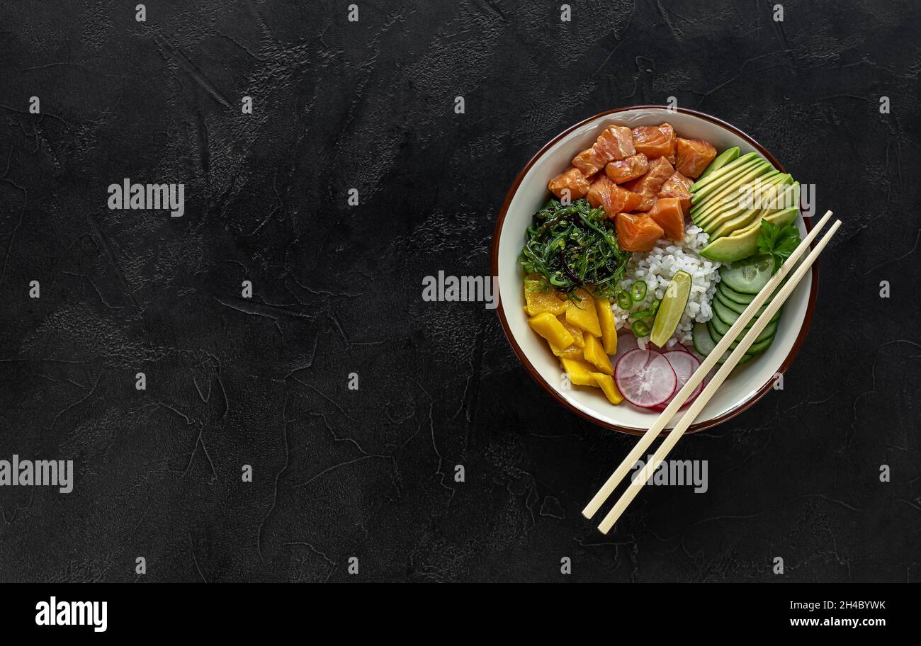 Salmon poke bowl with rice, mango, avocado, seaweed, radish, and ...