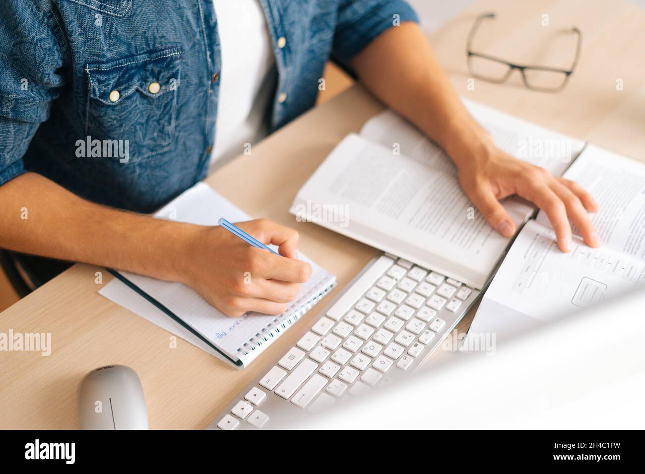 High-angle view of unrecognizable male student studying online from ...