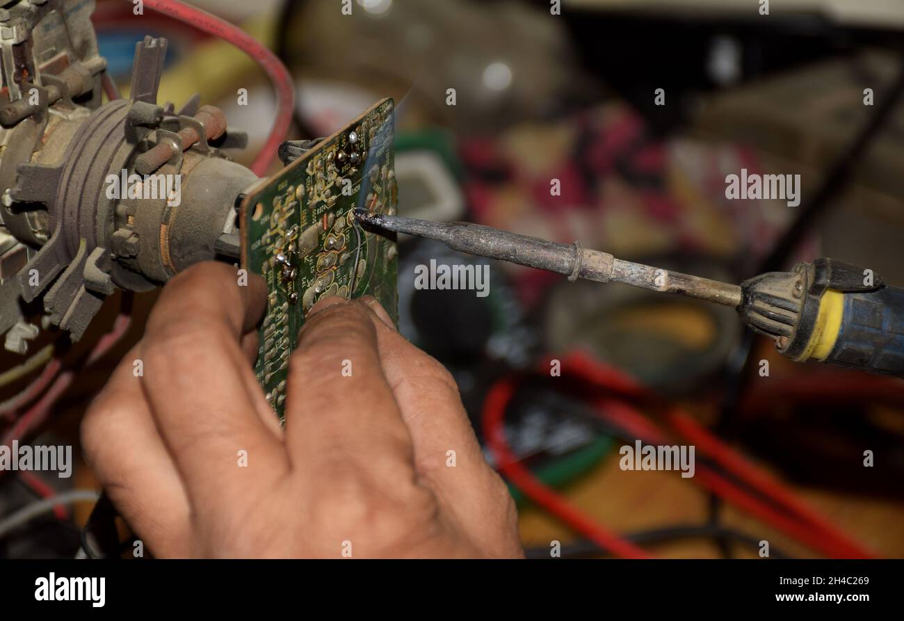 Hand of a TV mechanic or Technician soldering a circuit board of a ...